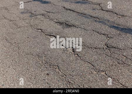 an asphalt road with a lot of holes and damage, a poorly made ...