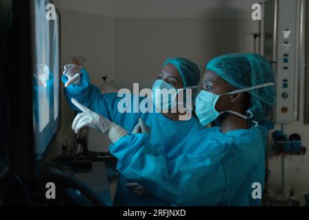 Diverse female surgeons looking at x-ray scans in operating theatre at ...