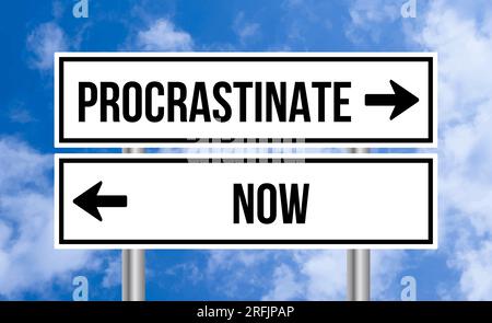 Procrastinate or now road sign on cloudy sky background Stock Photo - Alamy
