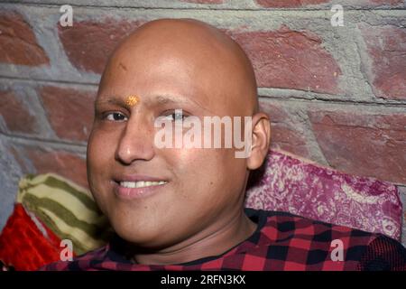 Indian bald and clean shaved young man lying smiling, brick wall in the ...