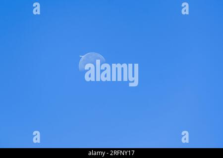 Daily Moon phase with plane in the blue sky Stock Photo - Alamy