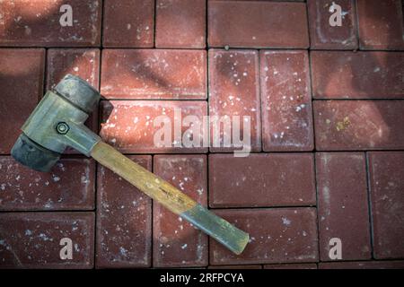 A hammer with rubber tips lies on the paving stones of the new pavement ...