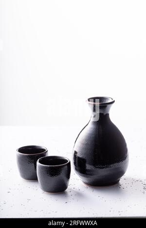 Unfiltered Japanese sake in small black ceramics. Method of serving ...