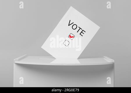 Paper with word Vote and tick sticking out of ballot box on light grey ...