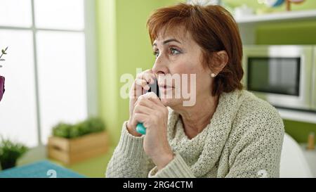 Mature hispanic woman vaping sitting on table at dinning room Stock ...