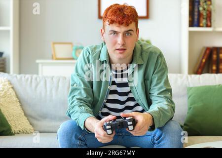 Young handsome redhead gamer man playing video game using headphones ...
