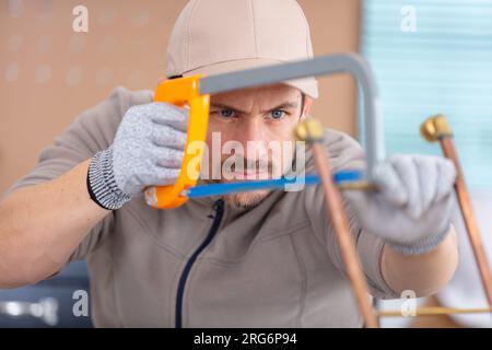 tradesman cutting copper pipe with hacksaw Stock Photo - Alamy