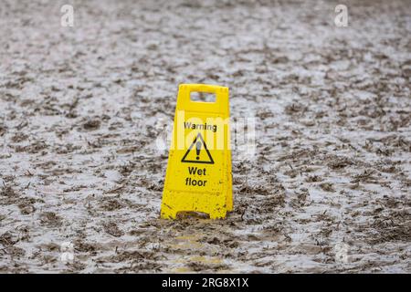 Muddy Wickham Festival 2023. Wet Floor sign placed in the mud Stock ...