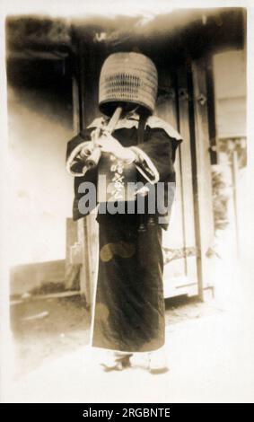 Komuso monk playing a bamboo shakuhachi flute with a woven basket on ...