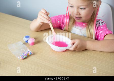 Cute Caucasian girl is making slime from scratch. Children education ...