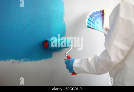 Master painter holds in his hands color palette with shades of blue ...