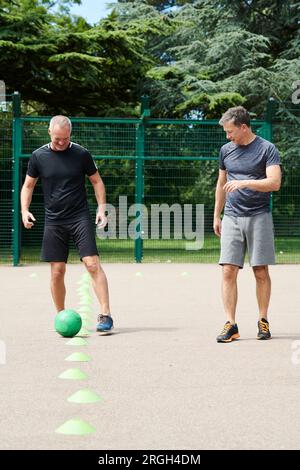 Mature men kicking ball on court Stock Photo - Alamy