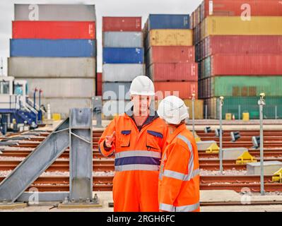 Dock workers talking by railroad tracks Stock Photo - Alamy