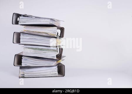 stack of black file folders full of documents against white background ...