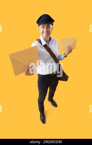Mature postman with parcel on yellow background Stock Photo - Alamy