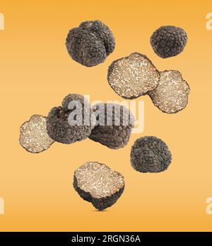 Cut and whole truffles falling on golden background Stock Photo - Alamy