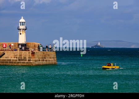 An inflatable rib enters the harbour at St Ives past the lighthouse on ...
