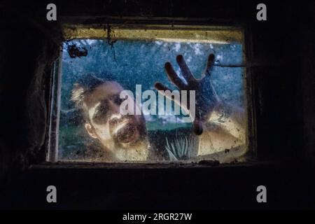 scary man behind window with spider nets at night Halloween horror ...