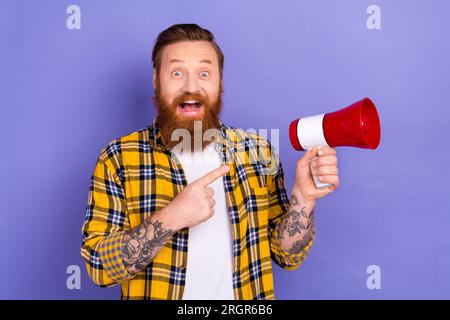 Portrait of astonished cheerful guy direct finger hand hold telephone ...