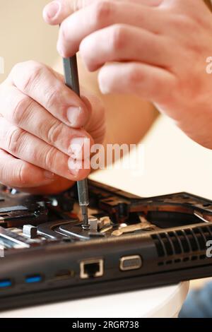 Repaiman with screwdriver fixing disassembled laptop parts. Technical ...