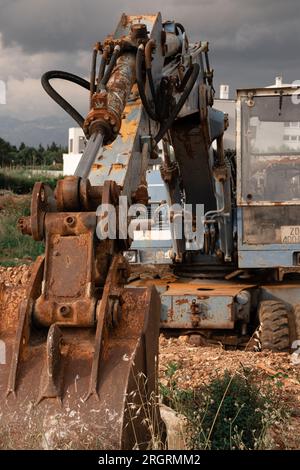 An old rusty blue excavator stands on a construction site. The rusty ...