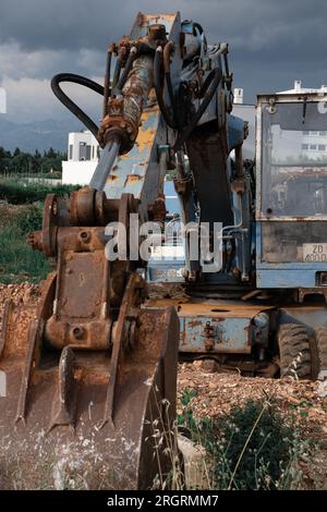 An old rusty blue excavator stands on a construction site. The rusty ...