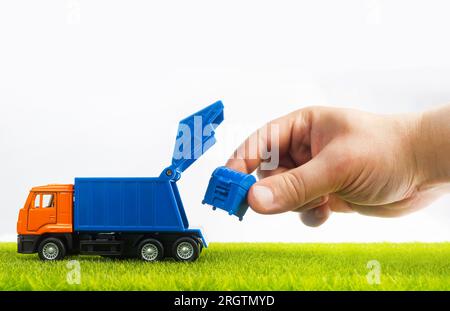 Photo of toy garbage truck with blue colored container on green lawn ...
