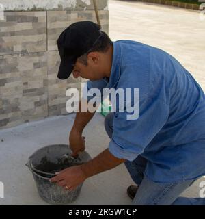 Image of a bricklayer mixing cement and glue in a bucket. Manual work ...