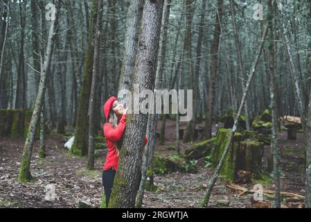 Woman with a pensive attitude admiring the forest leaning against a ...