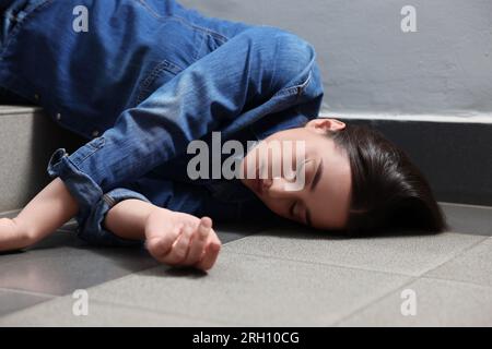 Unconscious woman lying on floor after falling down stairs indoors ...