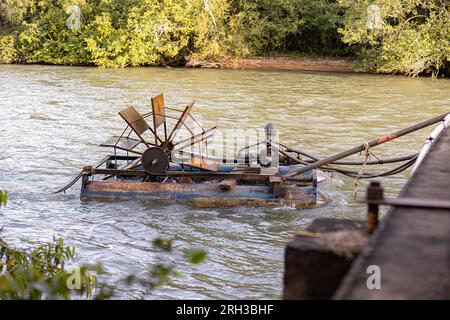 closeup on water pumping system by water wheel and pump floating in a ...
