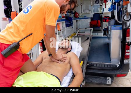 Lifeguard performing cardiopulmonary resuscitation (CPR) on a man on ...