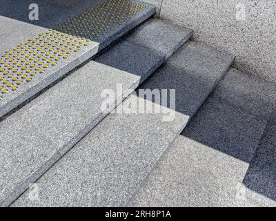 modern granite staircase with yellow nonskid bumpy markings. closeup ...