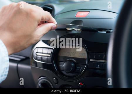 The man inserting CD to CD player in the car. Car audio system concept ...