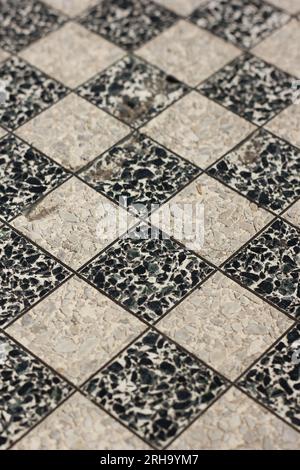 Repeating pattern of square tiles with perpendicular lines and gravel ...