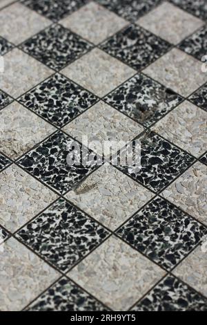Repeating pattern of square tiles with perpendicular lines and gravel ...