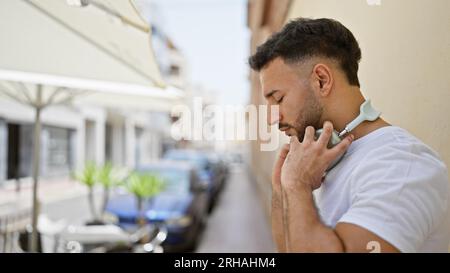 Young arab man taking headphones off with serious face at street Stock ...