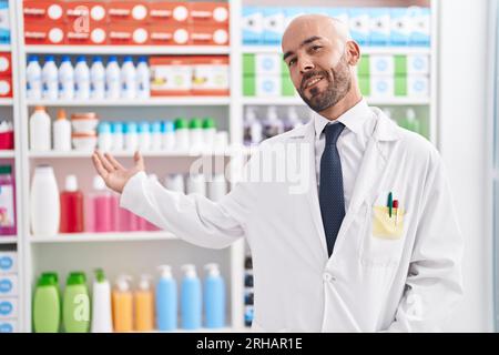 Young bald man pharmacist smiling confident holding medication on ...