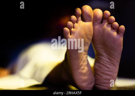 Feet of an Indian or Asian female dead body lying on floor in a dark ...