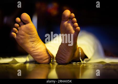 Feet of an Indian or Asian female dead body lying on floor in a dark ...