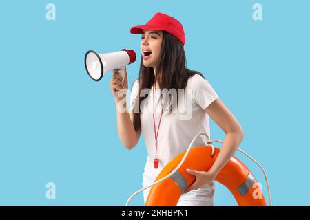 Female lifeguard with ring buoy shouting into megaphone on blue ...