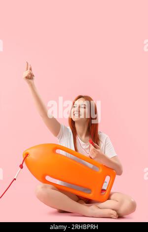 Female lifeguard with board on pink background Stock Photo - Alamy