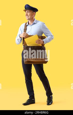 Mature postman with bag and envelope on yellow background, closeup ...