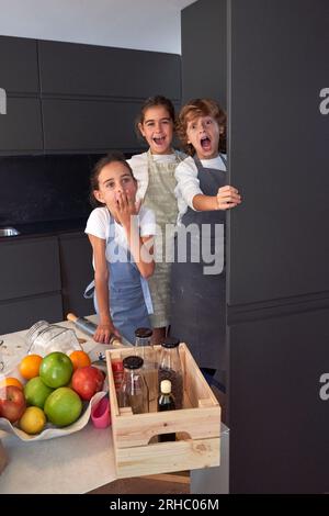 Kid in apron standing near granny making dough in kitchen Stock Photo ...