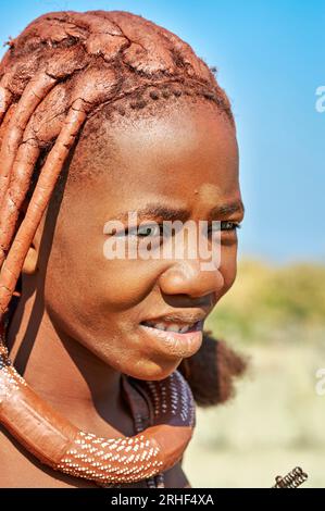 Pretty young Himba woman in the dark in front of her mud hut at the ...
