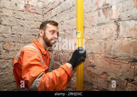 builder checking brick wall with spirit level Stock Photo - Alamy