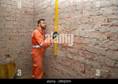 Young builder checking level Stock Photo - Alamy
