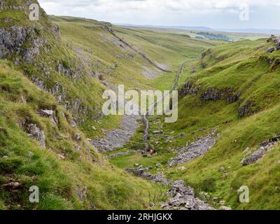 Hikers walking down the dry valley of Ing Scar between Malham Tarn and ...
