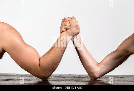 heavily muscled man arm wrestling a weak puny man Stock Photo - Alamy