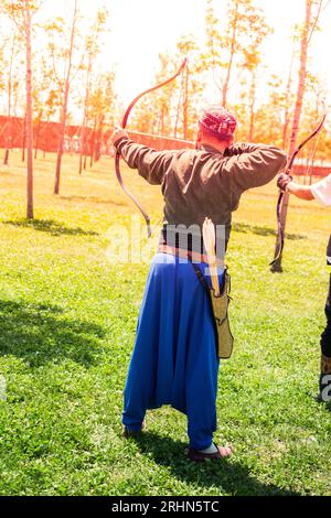 Archer with bow in traditional clothes shooting an arrow Stock Photo ...